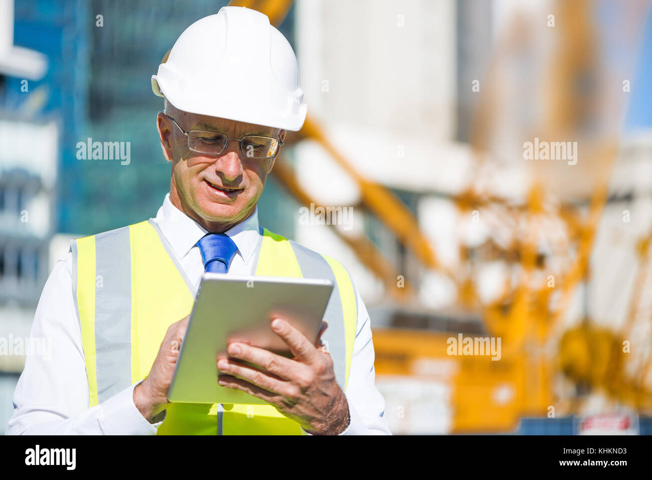 Construction manager controlling building site and tablet device in his ...