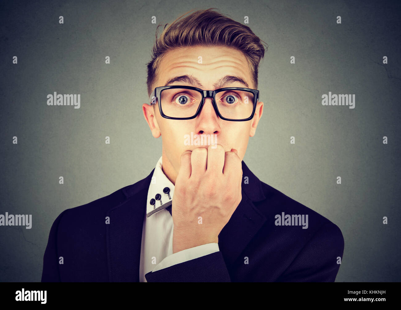 Preoccupied anxious business man in glasses biting his fingernails ...