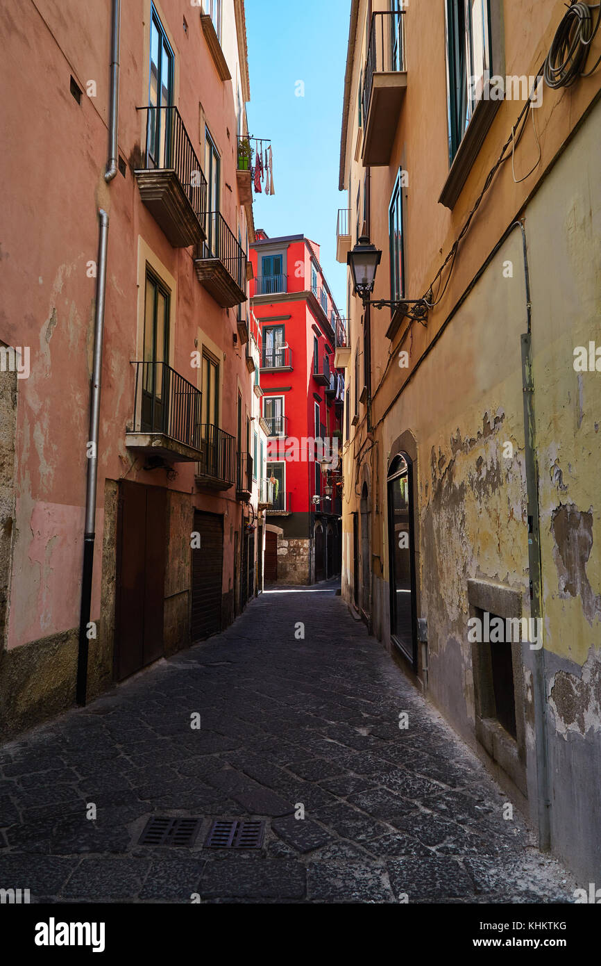 A narrow Italian street with shabby walls and a fragment of a bright ...