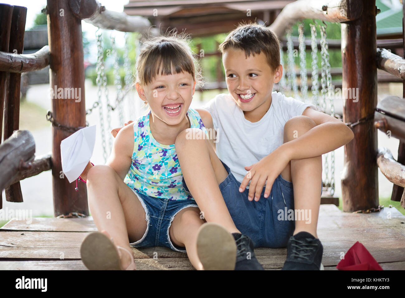 Two young caucasian children sitting next to each other with bent knees ...