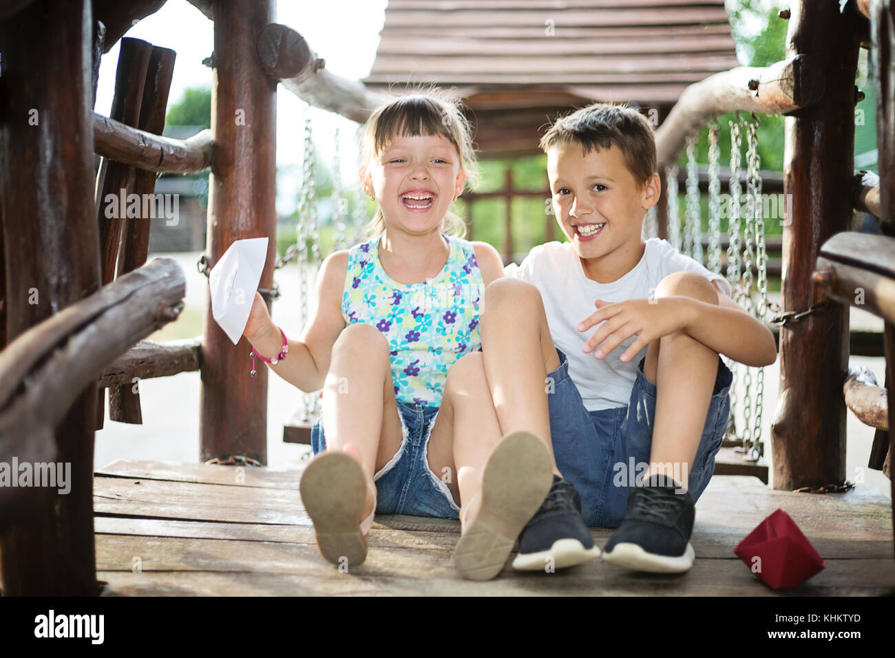 Two young caucasian children sitting next to each other with bent knees ...