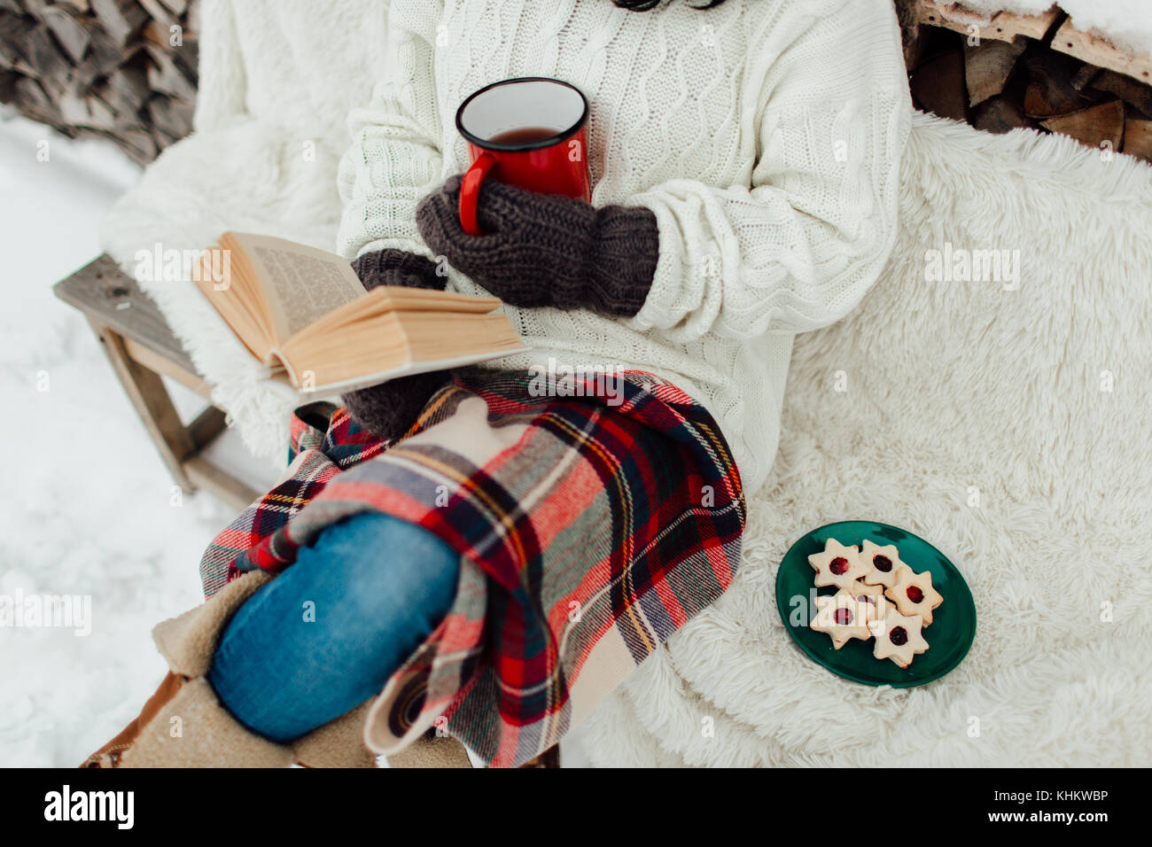Cropped image of a woman enjoying reading a book on a cold winter day ...