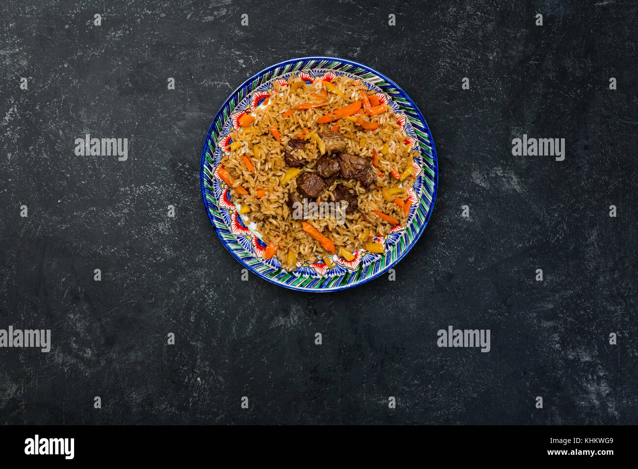Pilaf on plate with oriental ornament on a dark background. Central ...