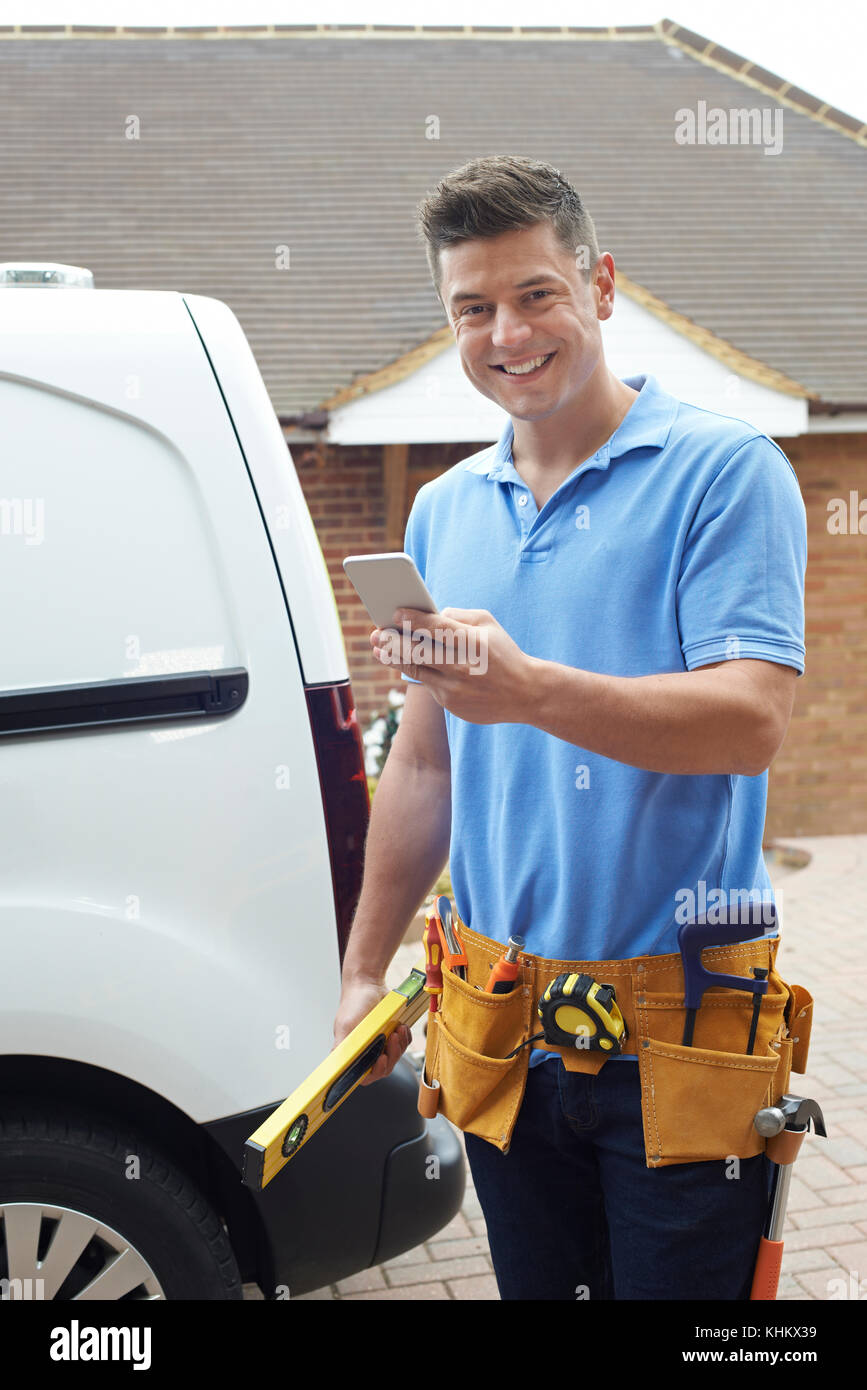 Builder With Van Checks Text Messages On Mobile Phone Outside House ...