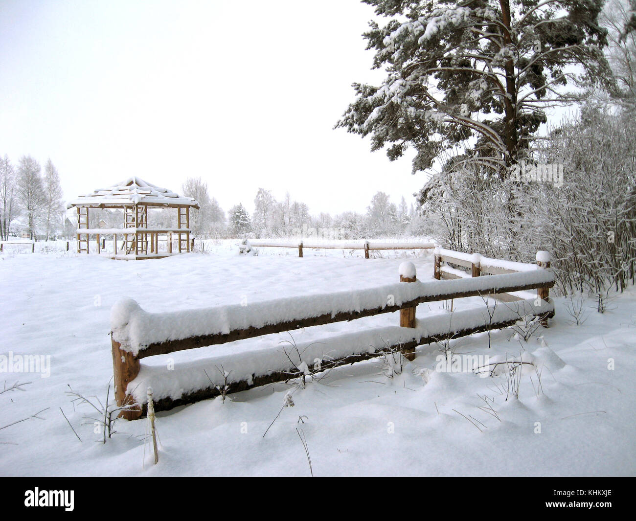 Country yard after snowfall with fence and trees covered with deep snow ...