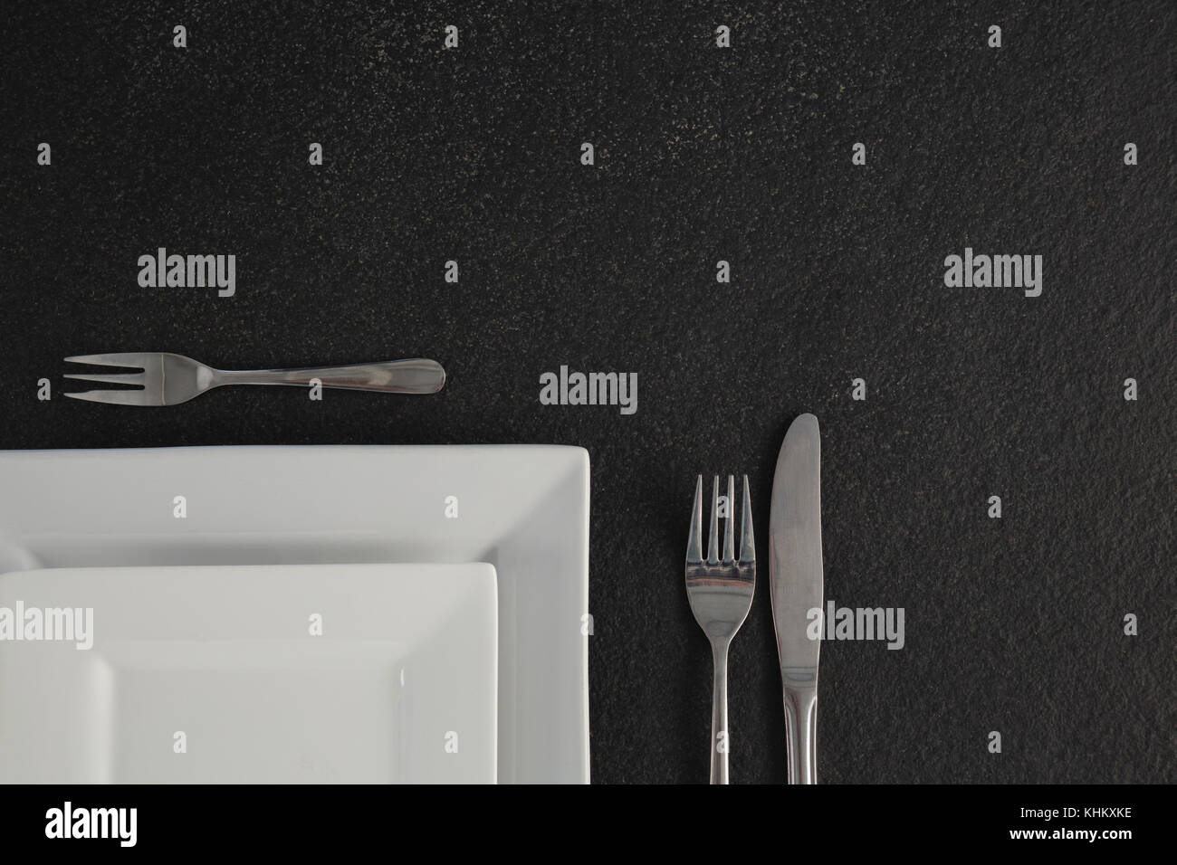 Close-up of square plates and cutlery set on a table Stock Photo - Alamy