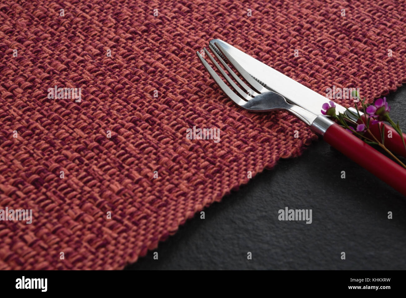Close-up of fork, butter knife with flower on placemat Stock Photo - Alamy