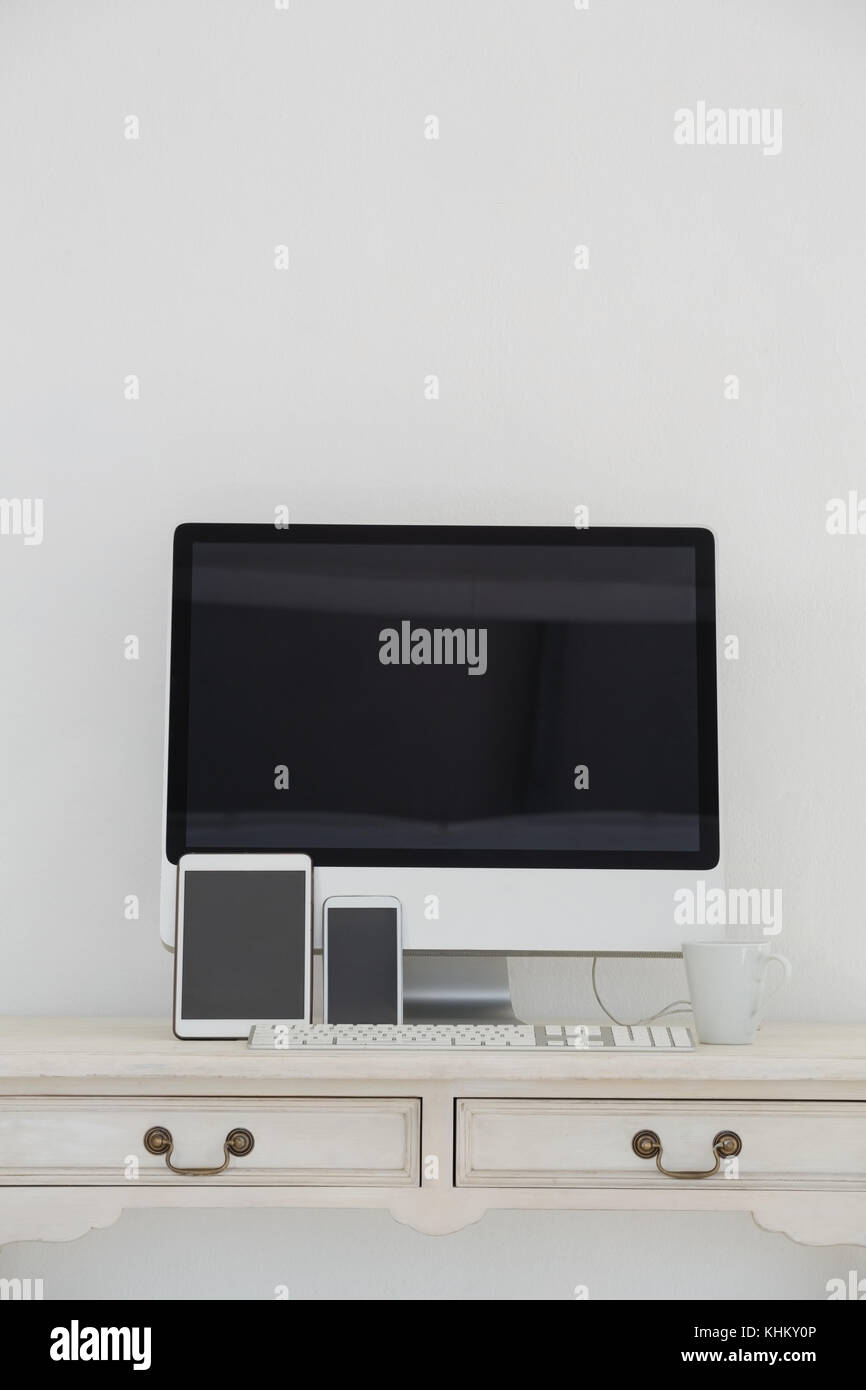 Various electronic gadgets on table against white wall Stock Photo - Alamy