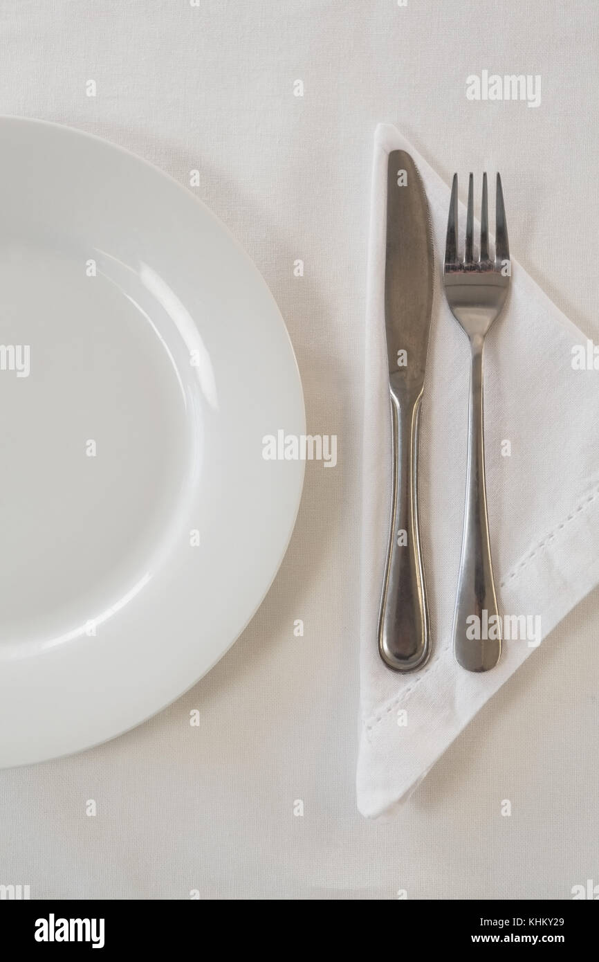 Close-up of white plate and cutlery set on a table Stock Photo - Alamy