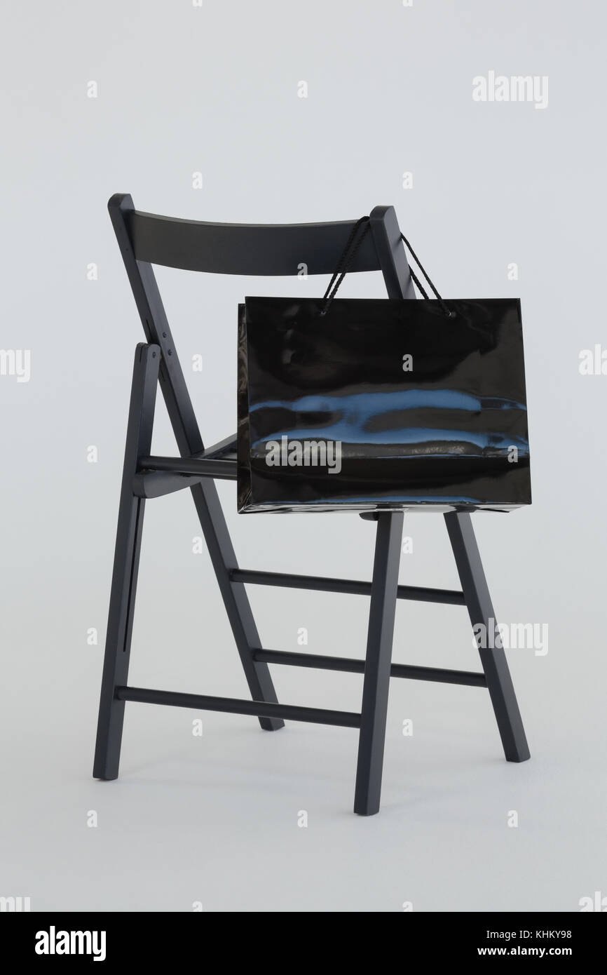 Close- up of shopping bag hanging on chair Stock Photo - Alamy