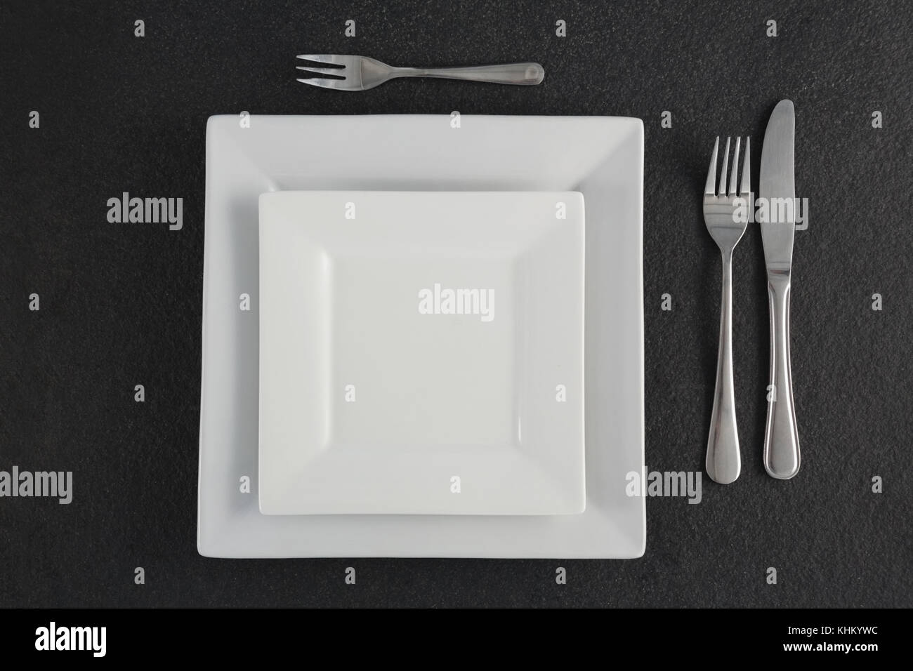 Close-up of square plates and cutlery set on a table Stock Photo - Alamy
