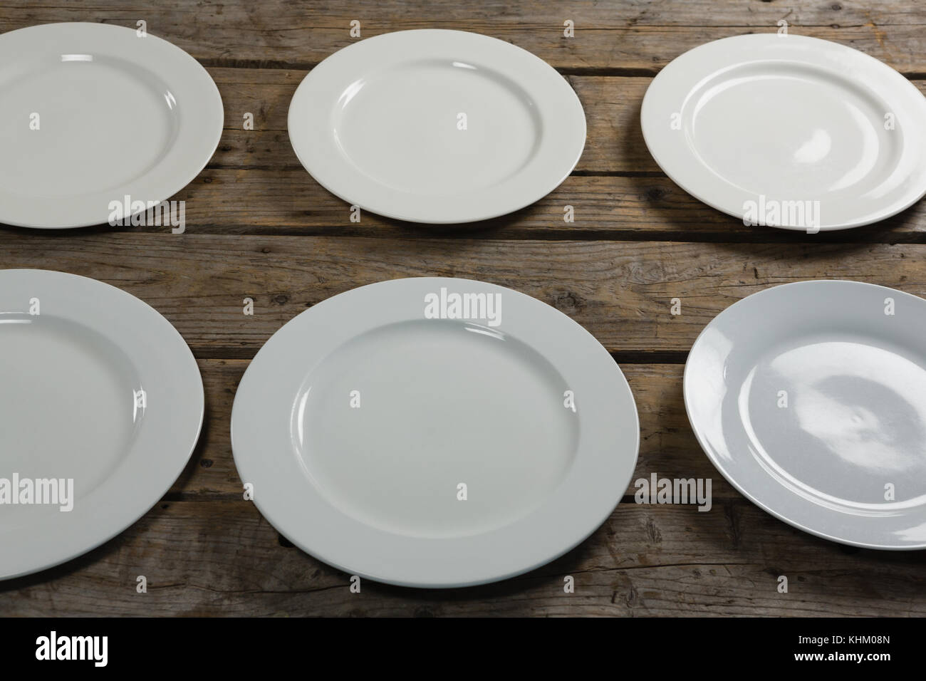 Empty plates arranged in row on wooden plate Stock Photo - Alamy