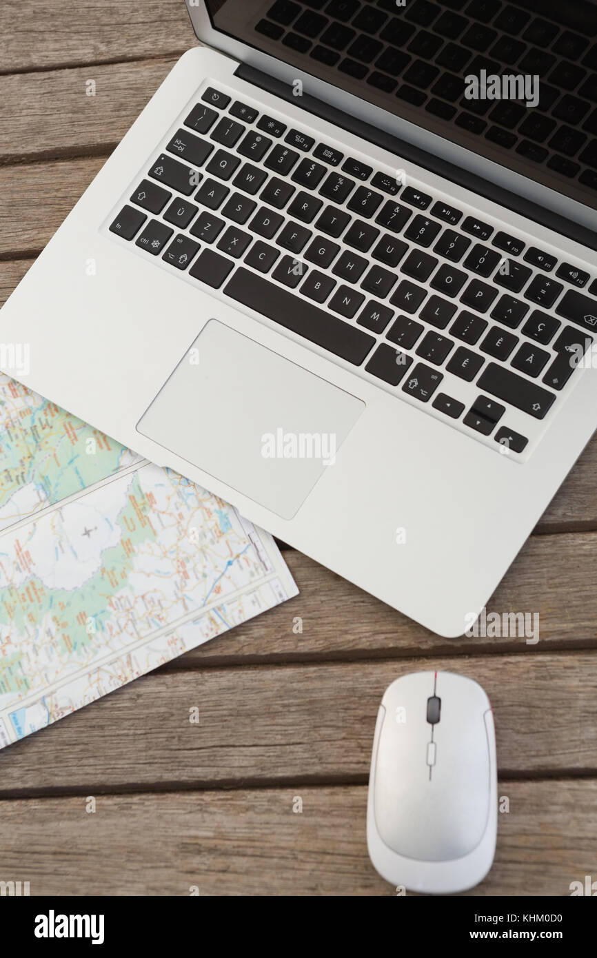 Overhead of laptop, mouse and world map on wooden plank Stock Photo - Alamy