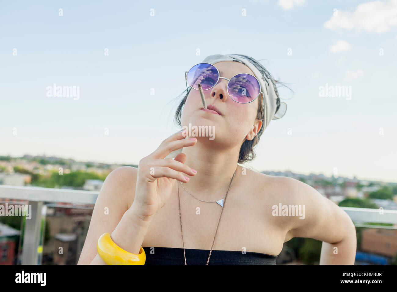 Young woman smoking on a rooftop Stock Photo - Alamy