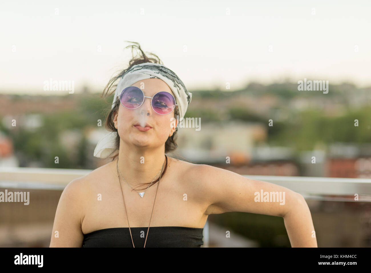 Young woman smoking on a rooftop Stock Photo - Alamy