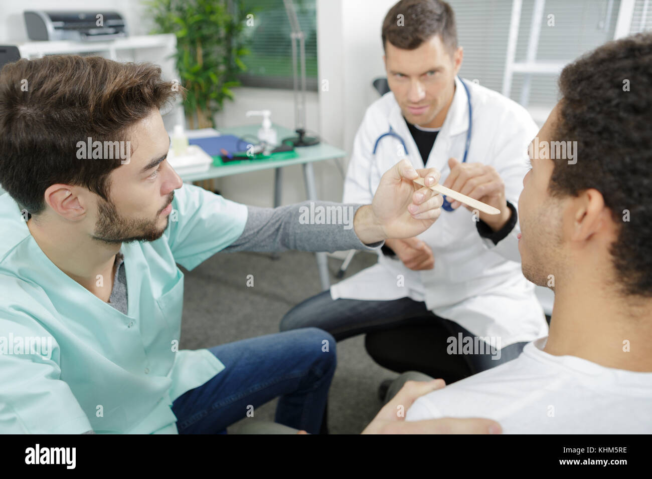male nurse sticking a stick on the patients tongue Stock Photo - Alamy