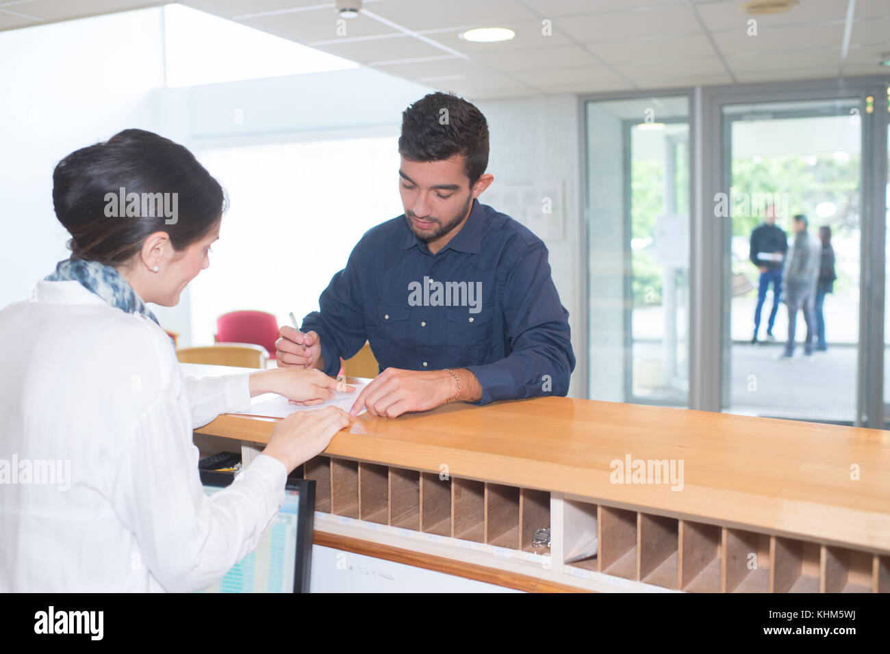 man checking in at reception desk Stock Photo - Alamy