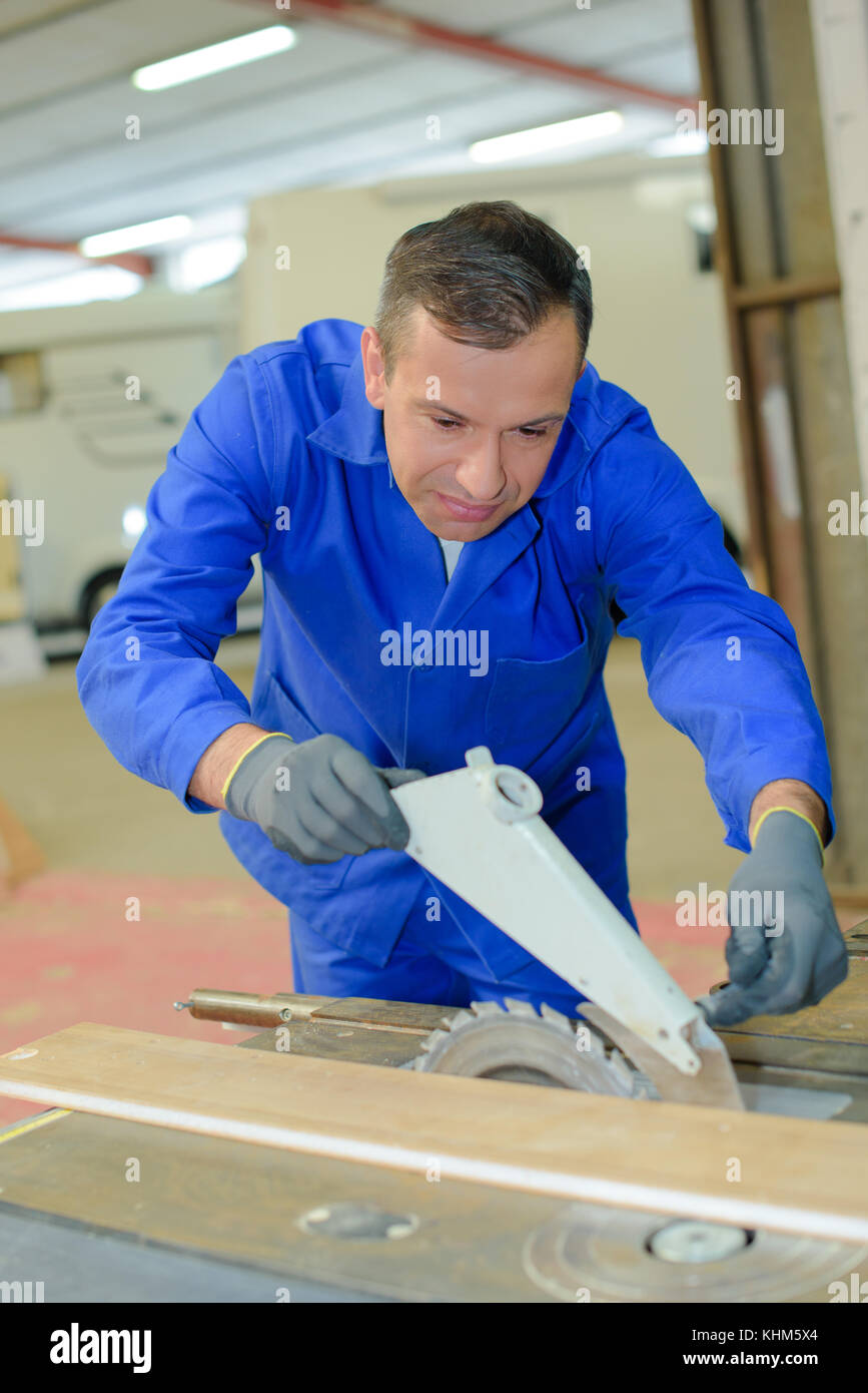 Man lifting guard of bench saw Stock Photo - Alamy