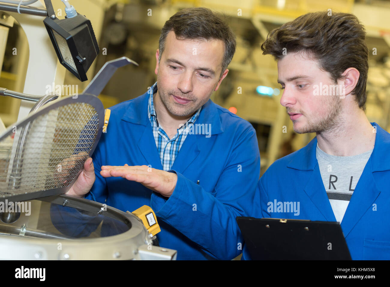 man showing working of machinery to apprentice Stock Photo - Alamy