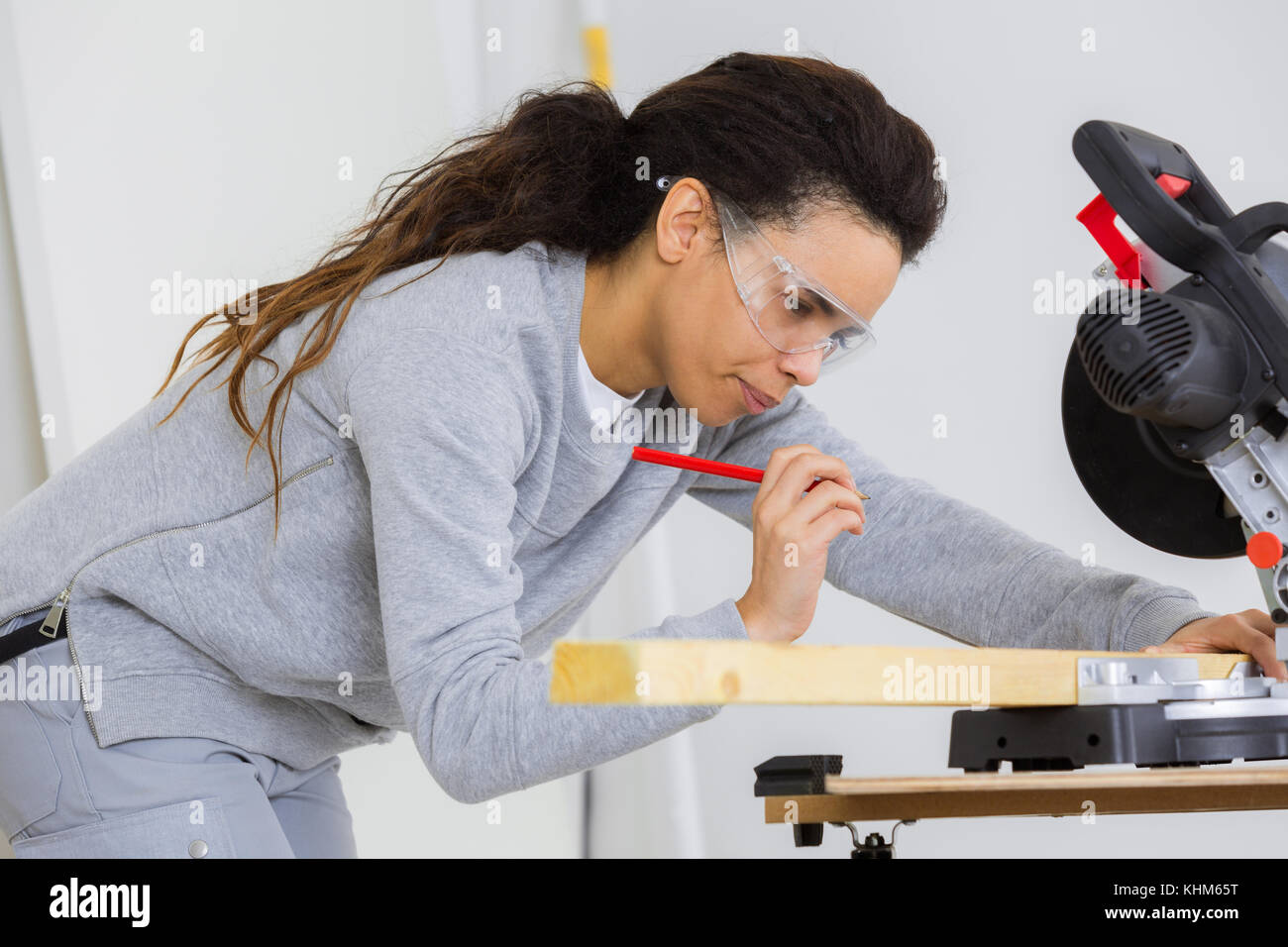 Woman using circular saw, marking wood Stock Photo - Alamy