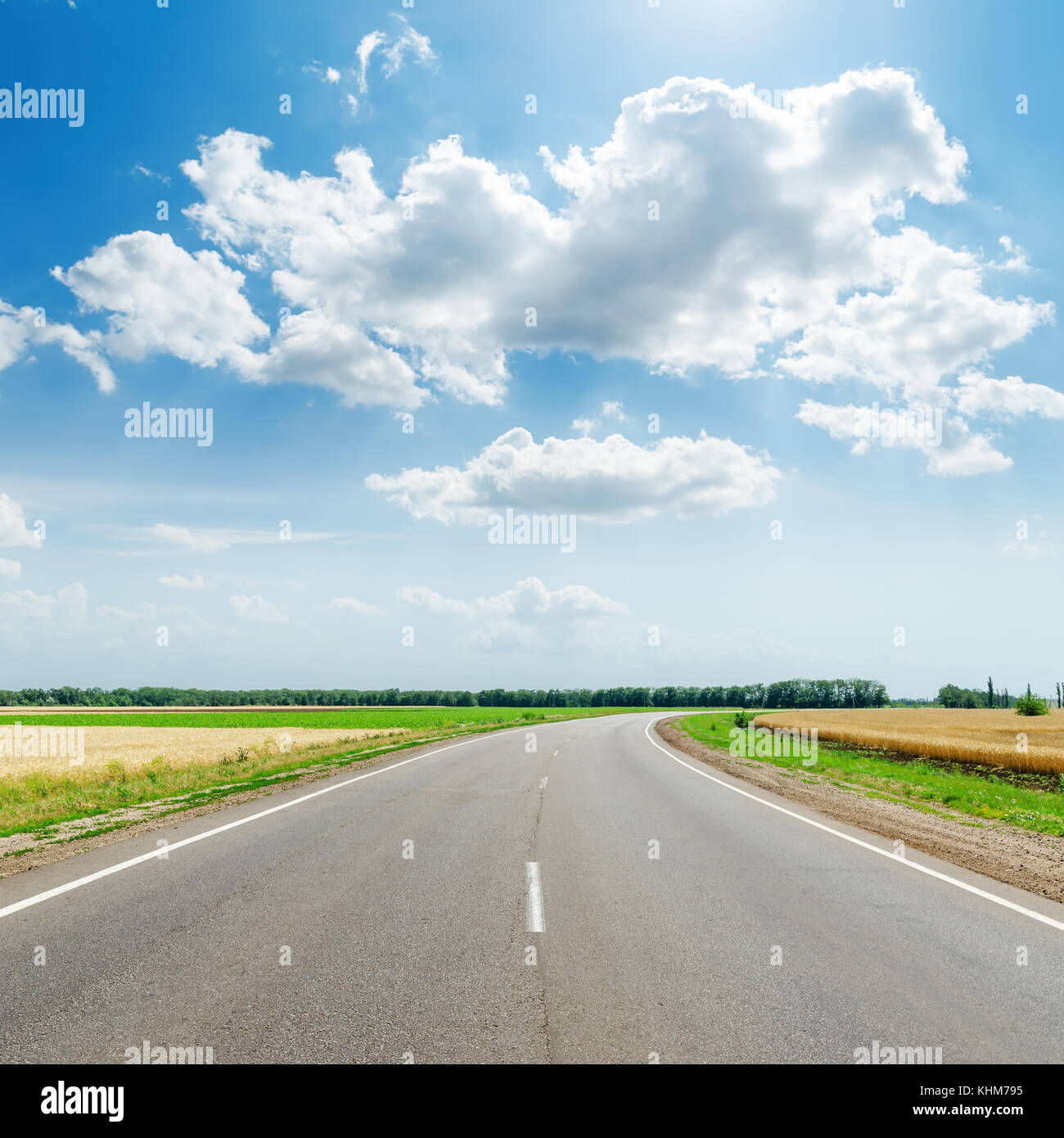asphalt road under clouds with sun Stock Photo - Alamy