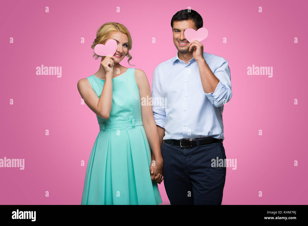 Beautiful young couple holding big pink hearts. Blond woman in mint ...