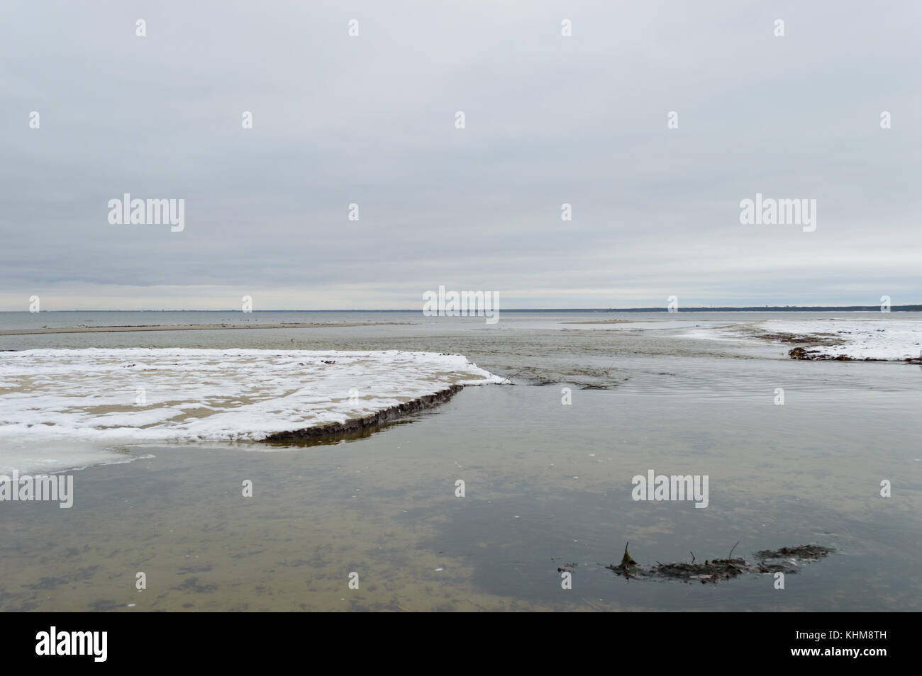 frozen rocky sea beach with snow and ice with clouds and stormy water ...