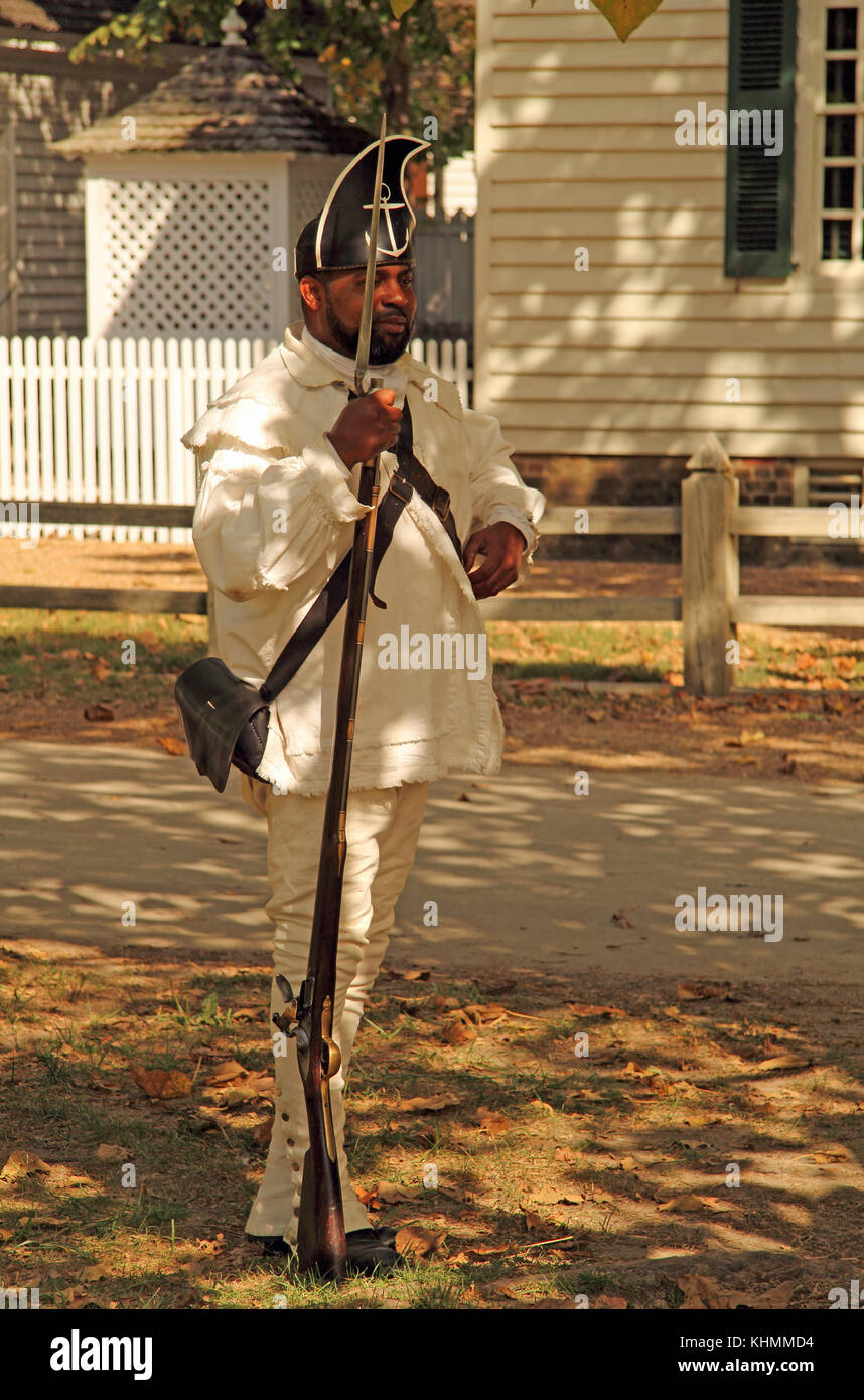 A soldier in period dress stands at attention with musket at his side ...