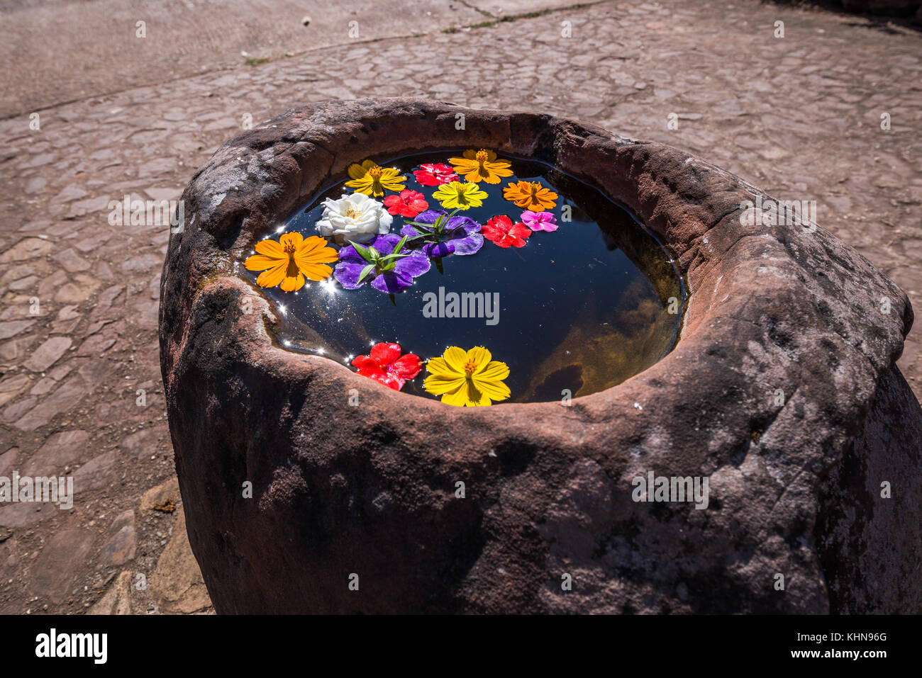 Stone well with colorful flower on top of water Stock Photo - Alamy