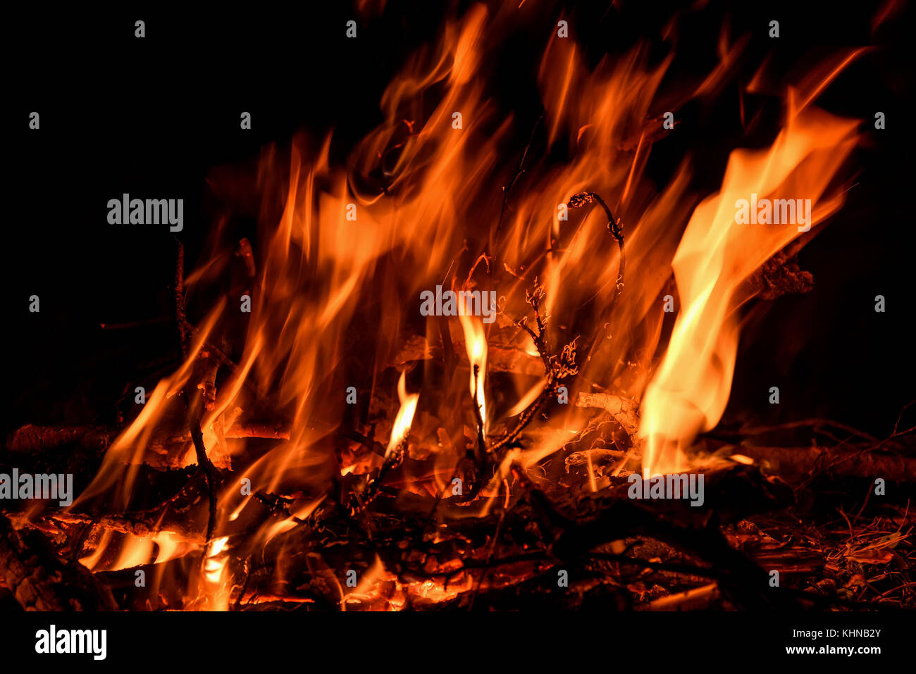 Red and orange spurts of flames, charcoal from the fire, wood and twigs ...