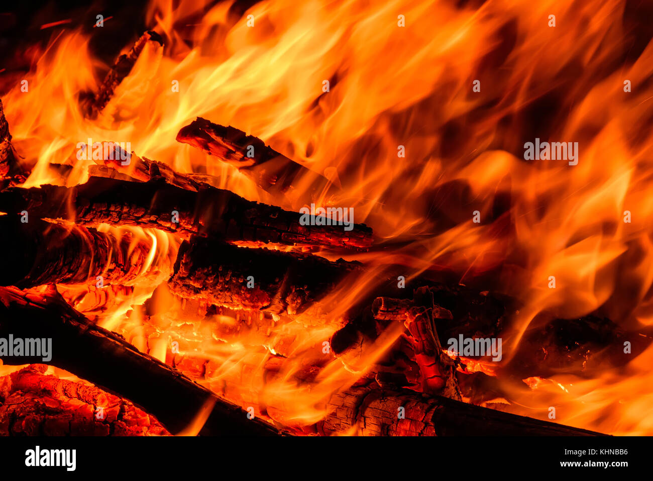 Big red and orange flames raging fire, wood and embers in the fire on a ...