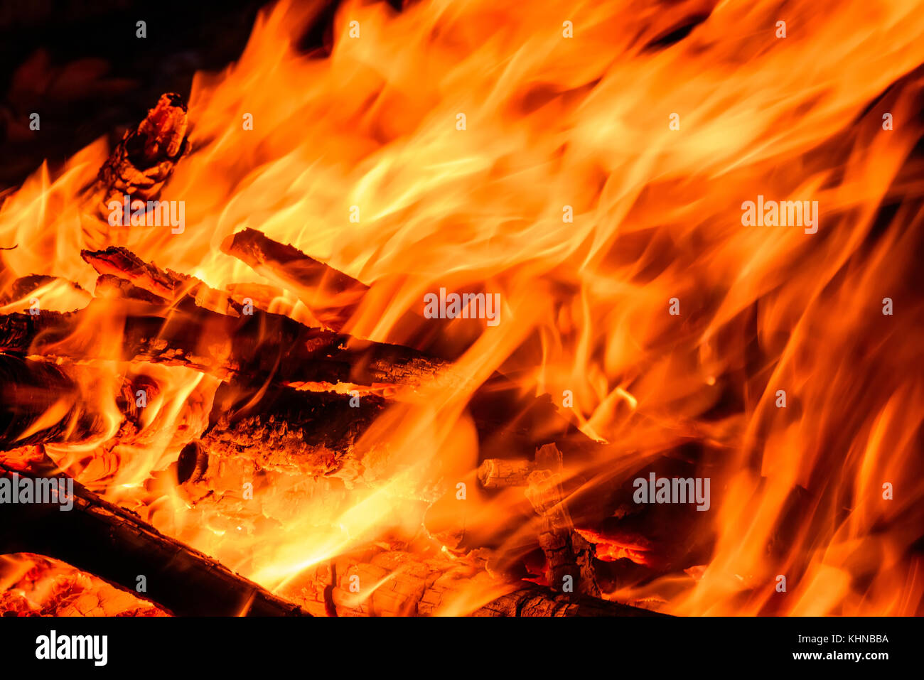 Big red and orange flames raging fire, wood and embers in the fire on a ...