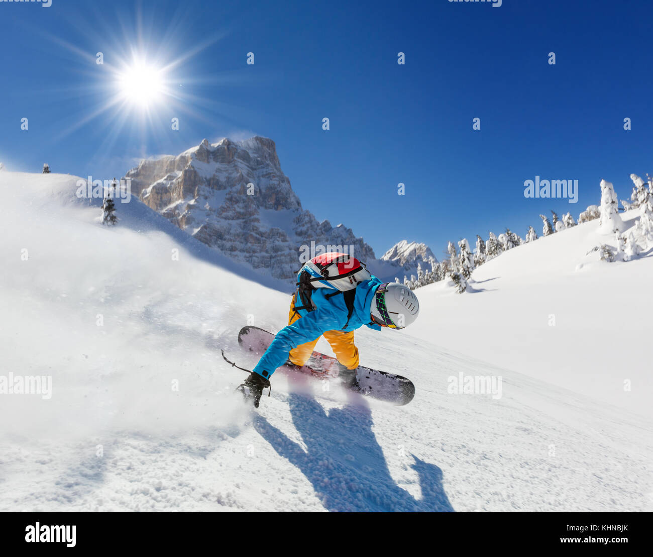 Snowboarder running downhill in beautiful Alpine landscape. Blue sky on ...