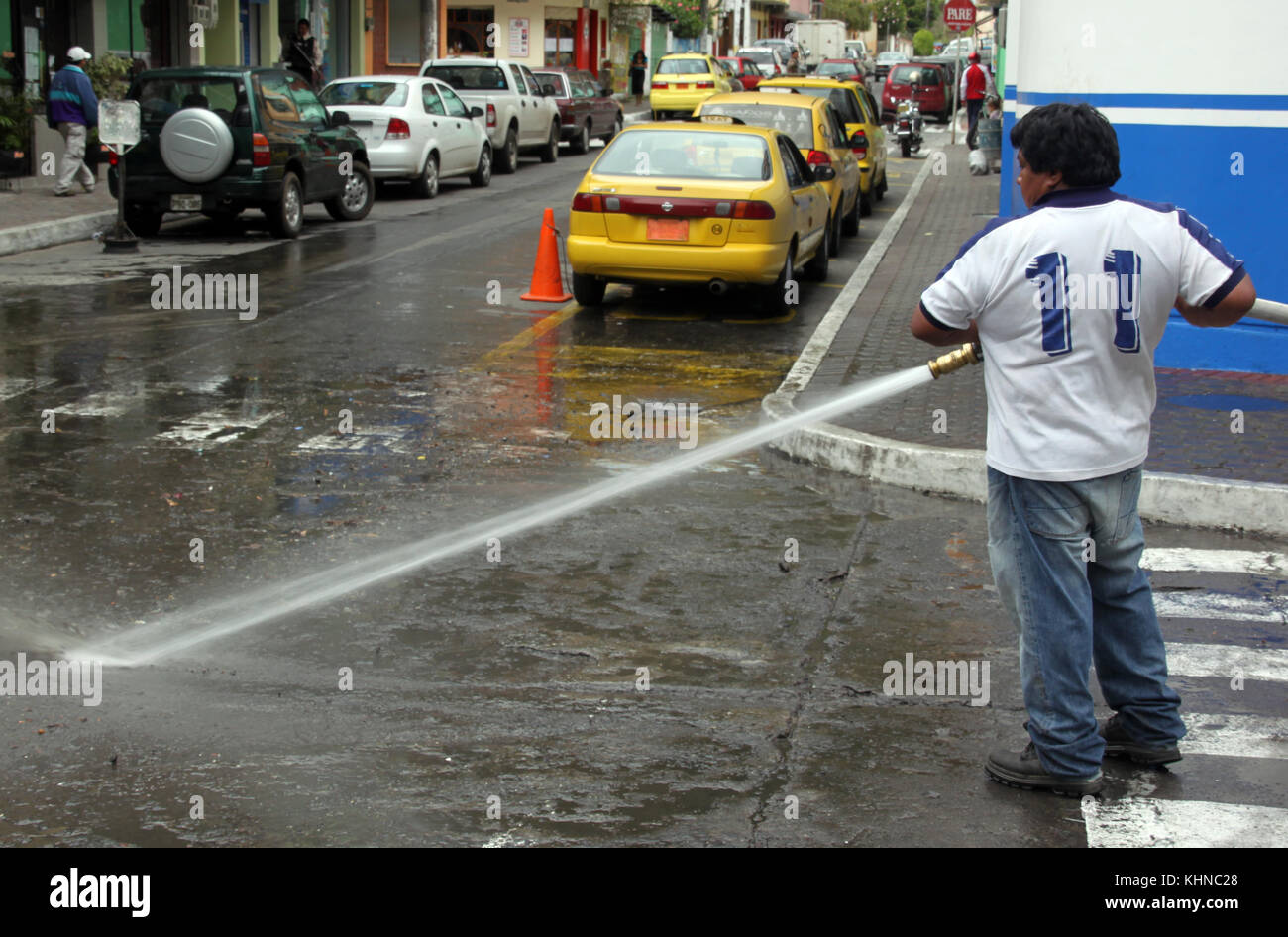 Man with water cleaning the street Stock Photo - Alamy