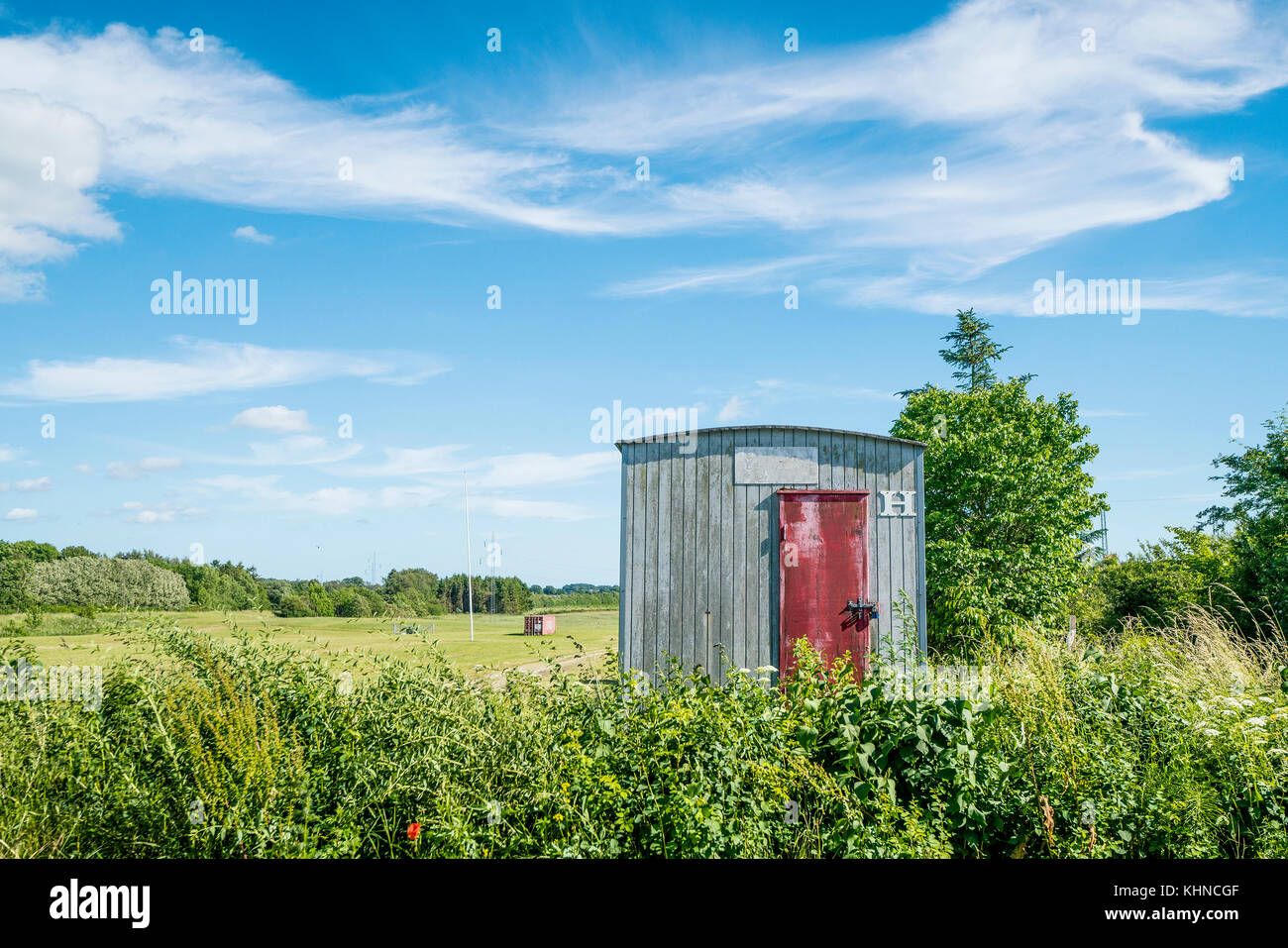 Wooden shed on a rural field in a countryside with green fields and ...
