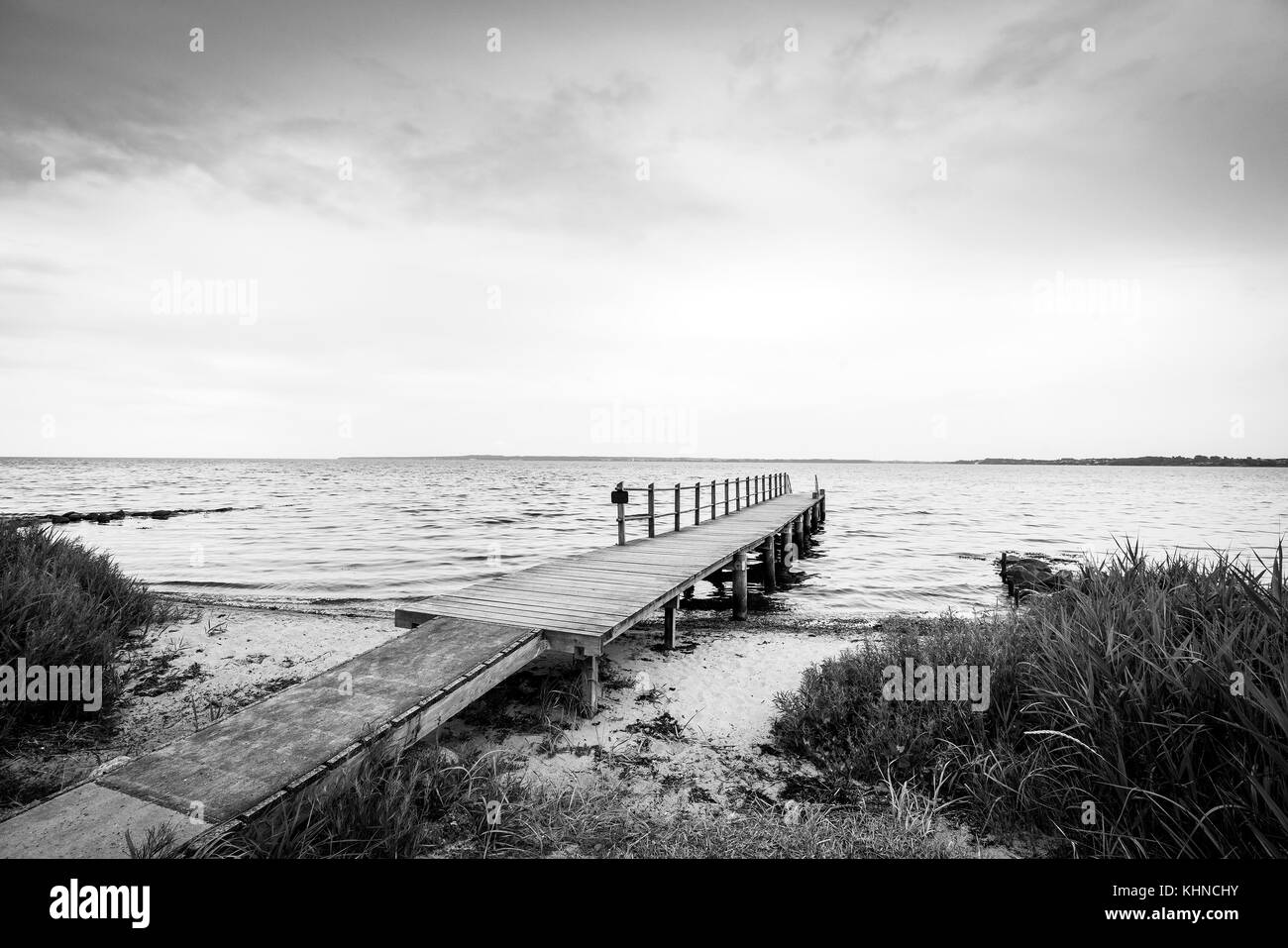 Pier on a Scandinavian beach in black and white with cold dark water on ...