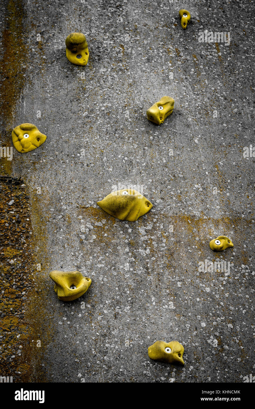 Climbing wall with yellow handles on concrete in vertical alignment ...