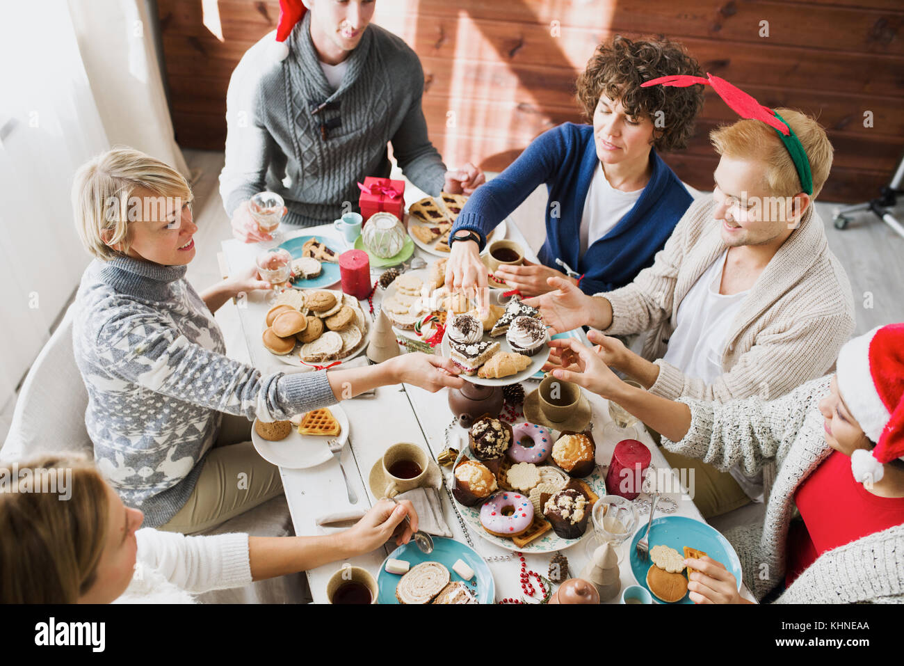 Young woman offering her guests to take fresh croissants and cupcakes ...