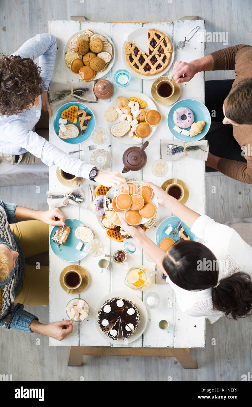Overview shot of friends sitting by festive table and having tea with ...
