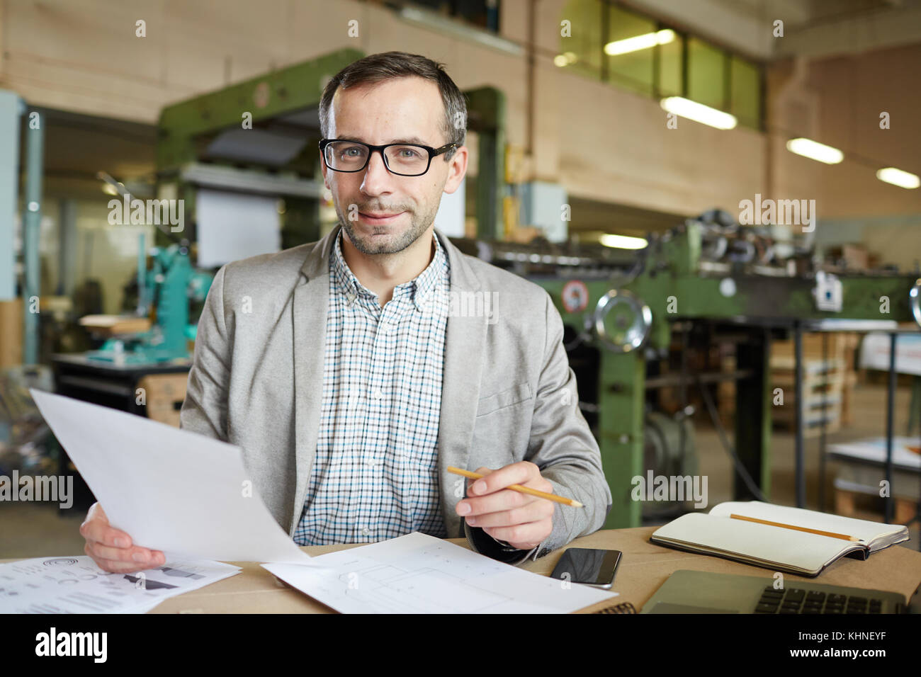 Successful engineer with paper looking through technical documents in ...