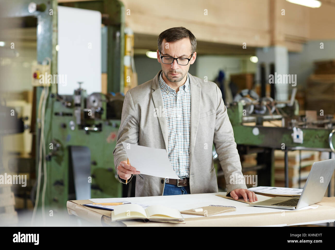 Master of engineering team standing by workplace and reading document ...
