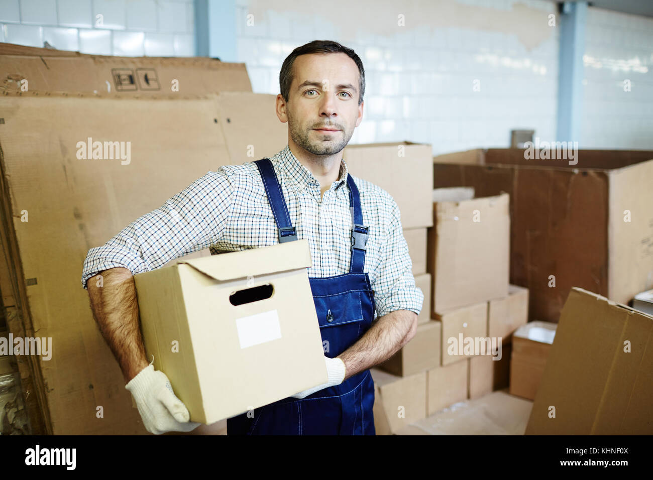 Middle-aged worker carrying boxes with details to storage room Stock ...
