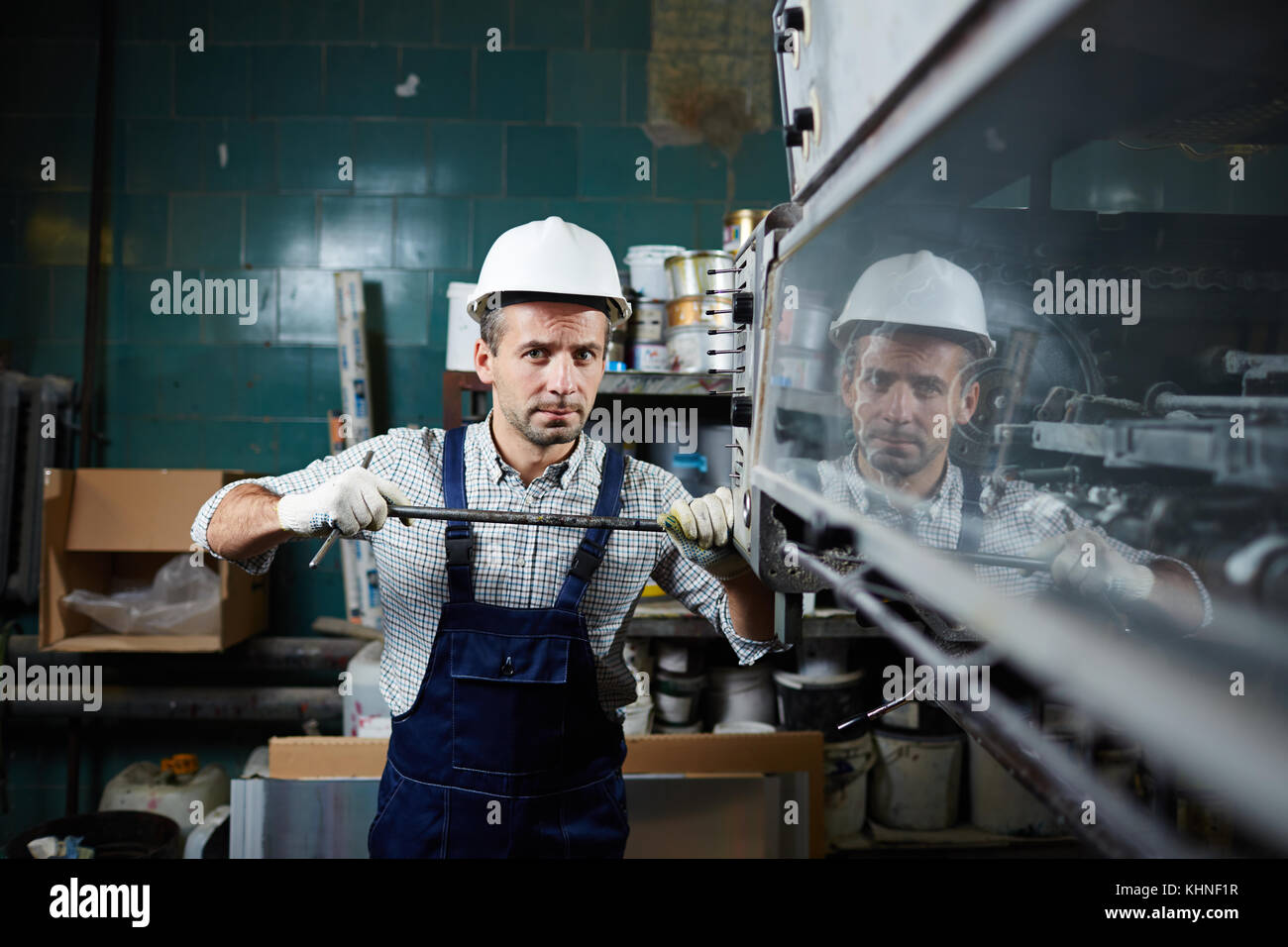 Worker in overall and harhat repairing industrial equipment Stock Photo ...
