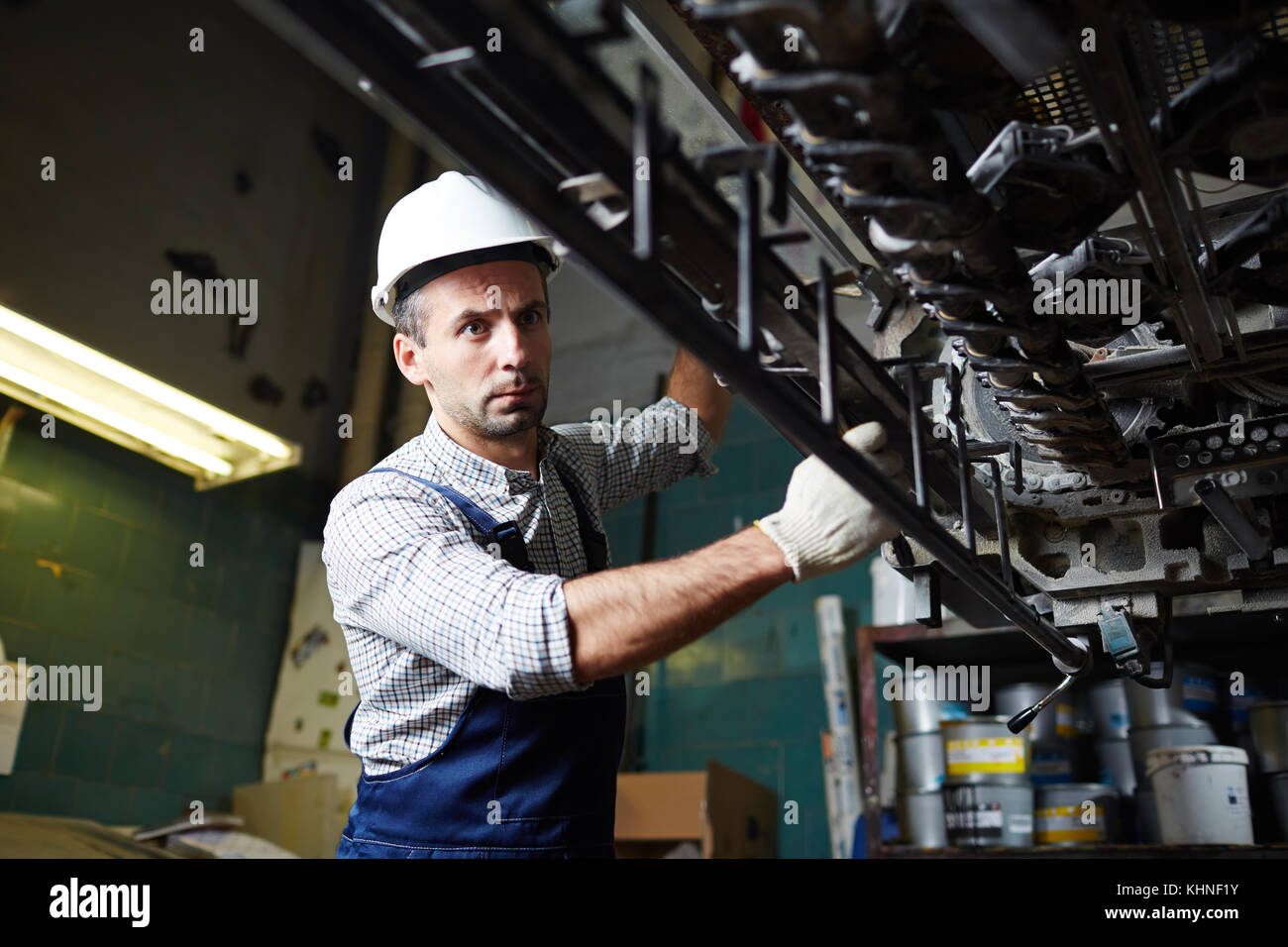 Engineer in uniform working by huge machine and producing industrial ...