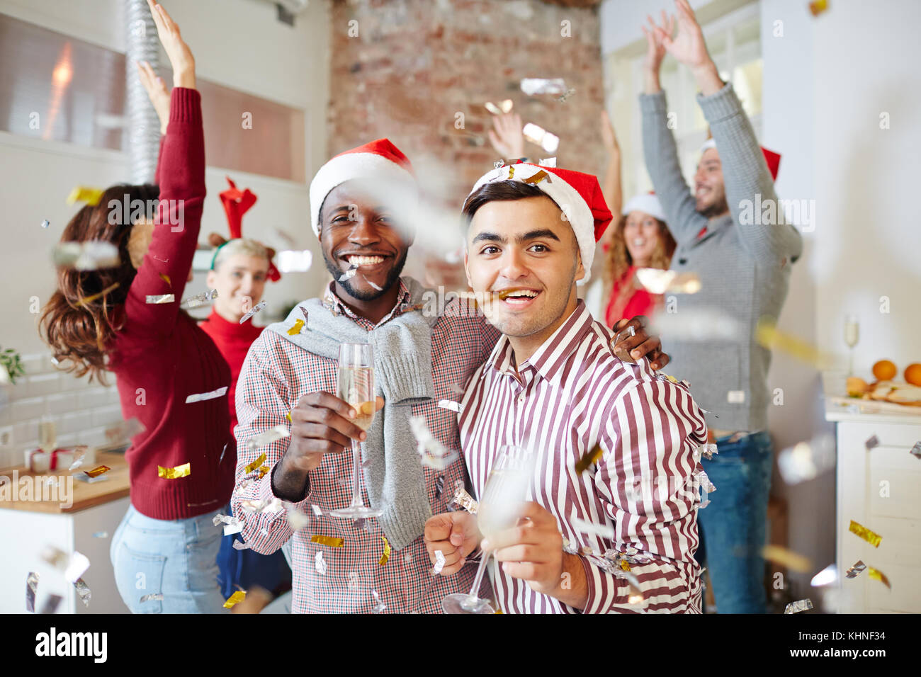 Laughing intercultural guys with champagne enjoying xmas party with ...