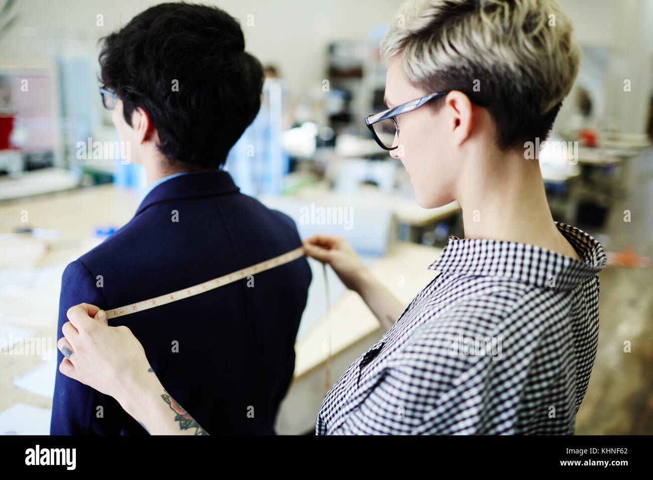 Contemporary seamstress measuring width of back of her client jacket ...
