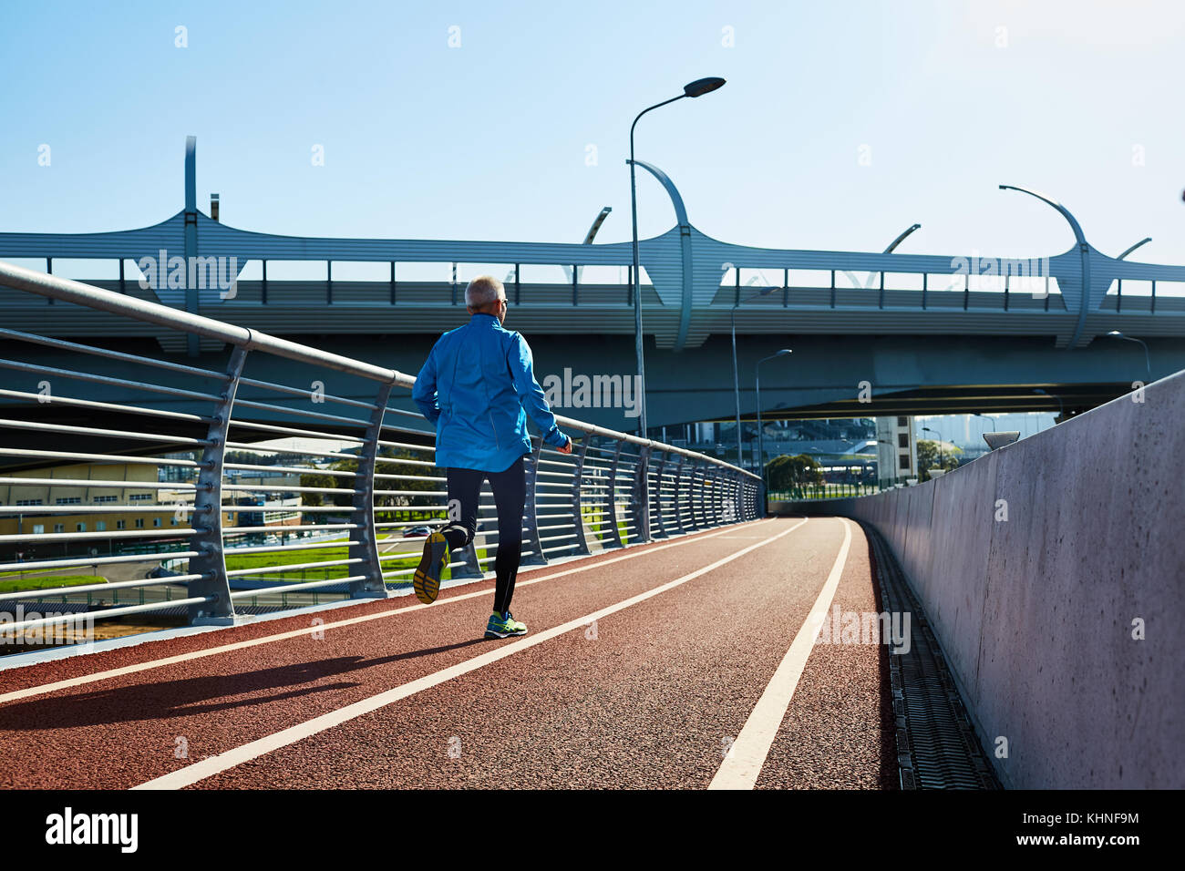 Rear view of contemporary sportsman running down urban road in the ...