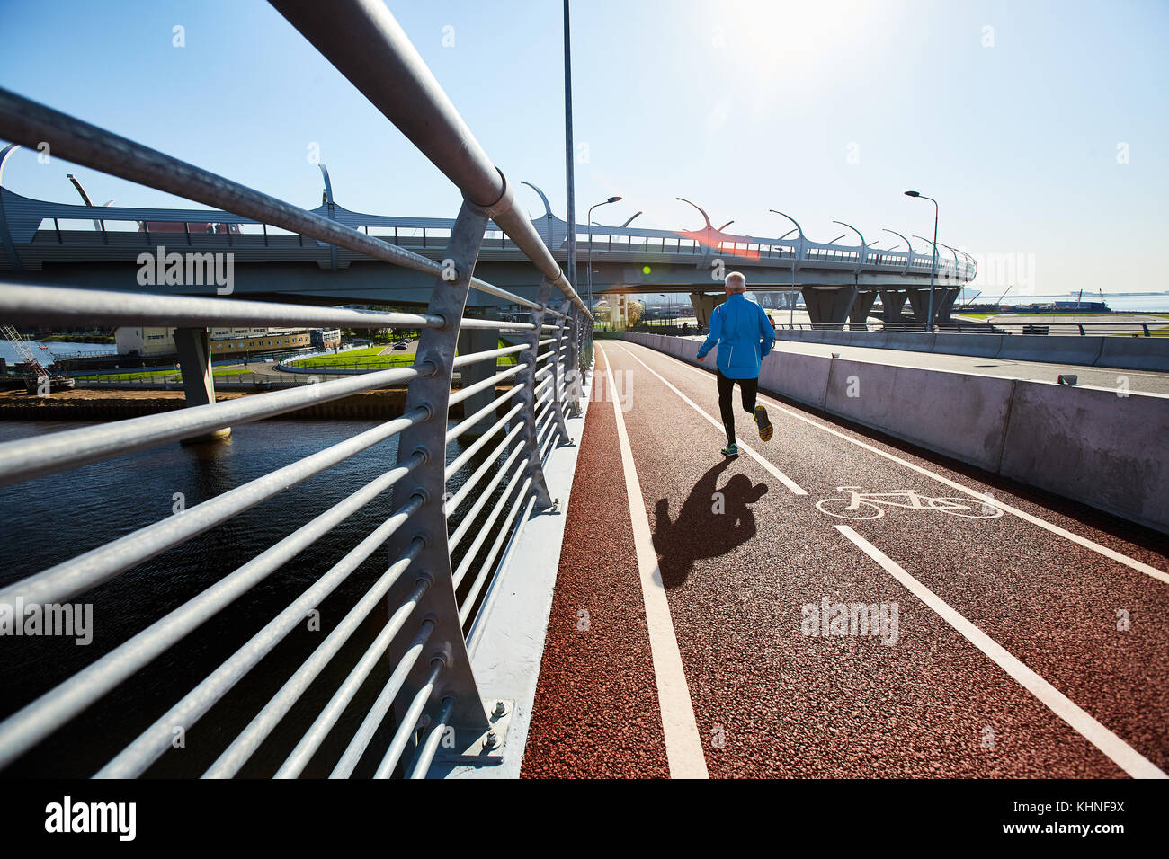 Perspective of bridge railings by riverside and active man running ...
