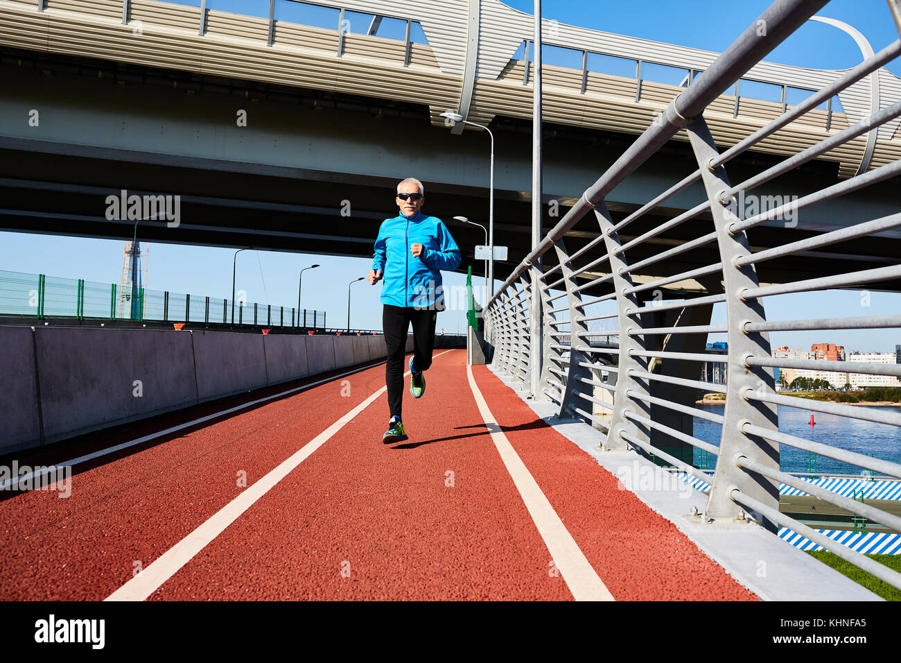 Retired active man running down bridge in urban environment Stock Photo ...