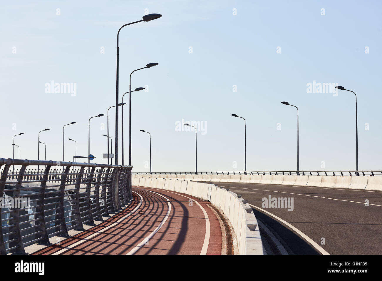 Empty cycling road turning left with street lamps all along Stock Photo ...